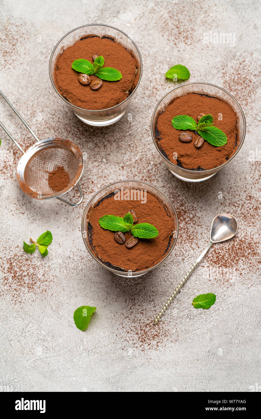 Classic tiramisu dessert in a glass cup and strainer with cocoa powder ...