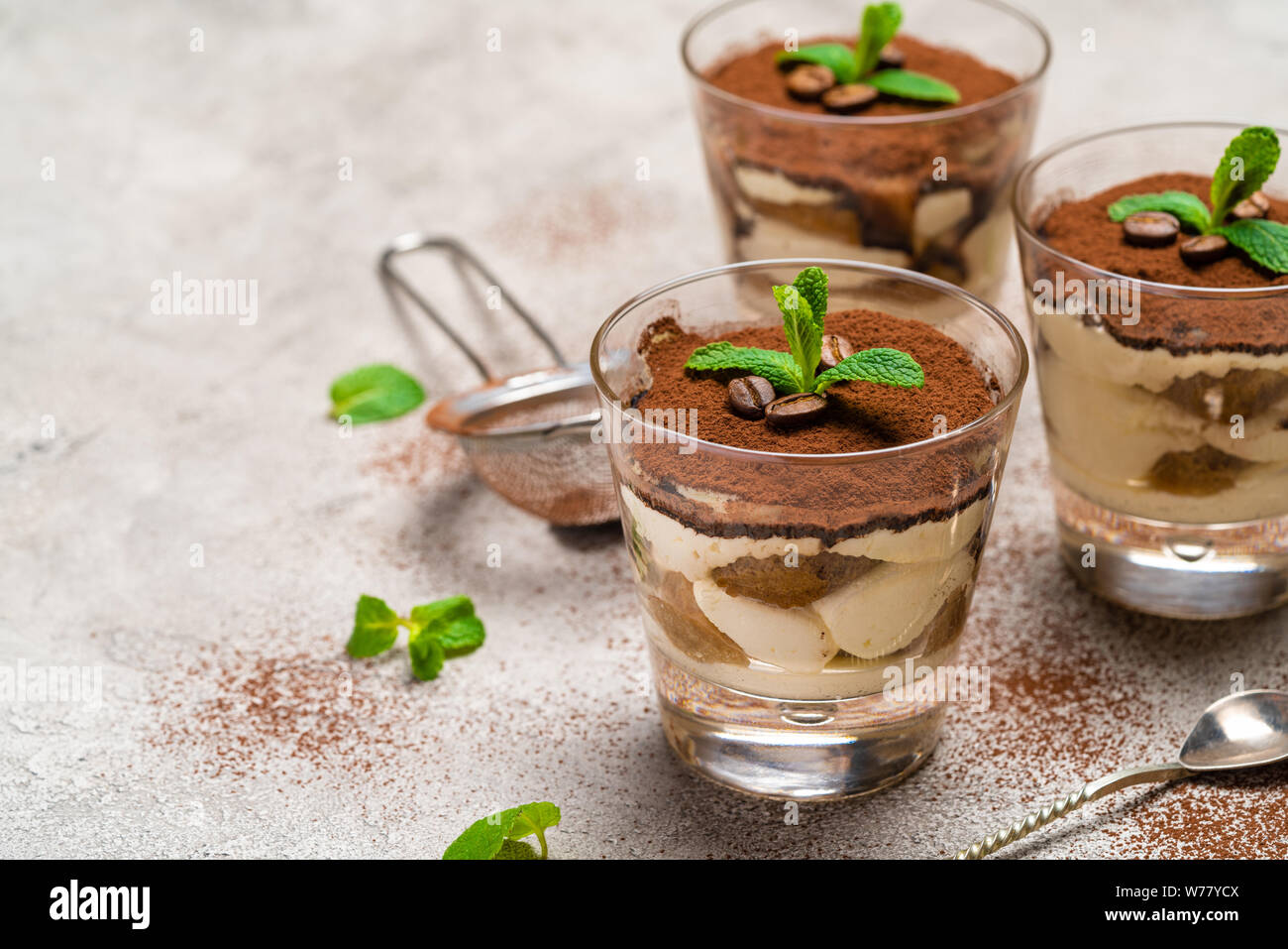 Classic tiramisu dessert in a glass cup and strainer with cocoa powder ...