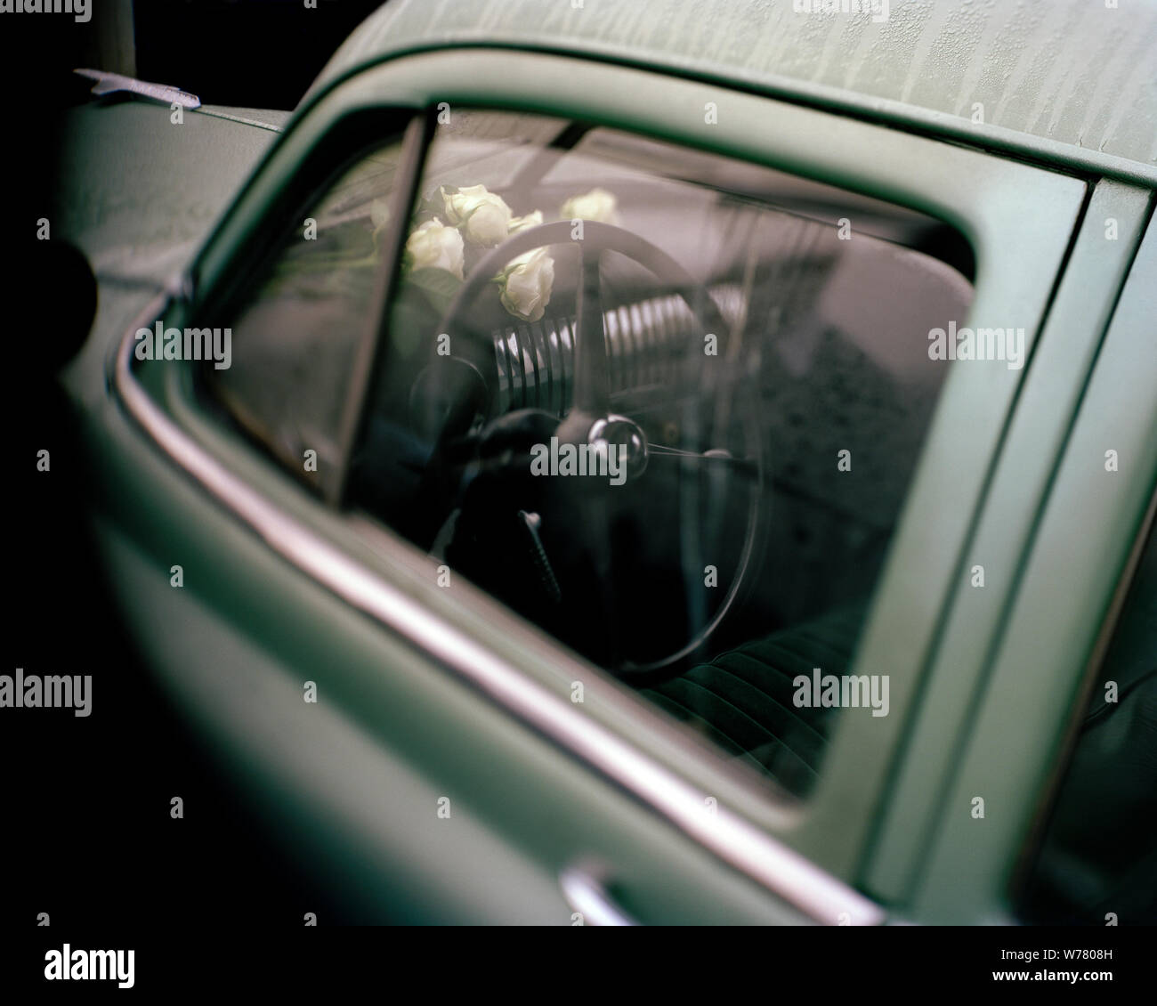 View through the window into a vintage car with roses on the dashboard ...