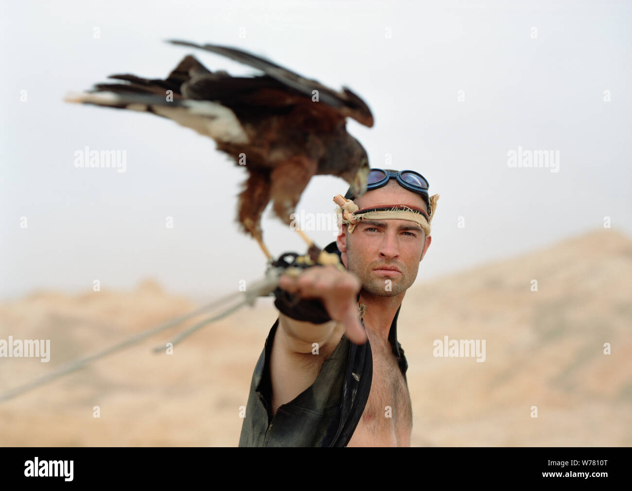 Portrait of a young man standing with a bird of prey perched on his ...
