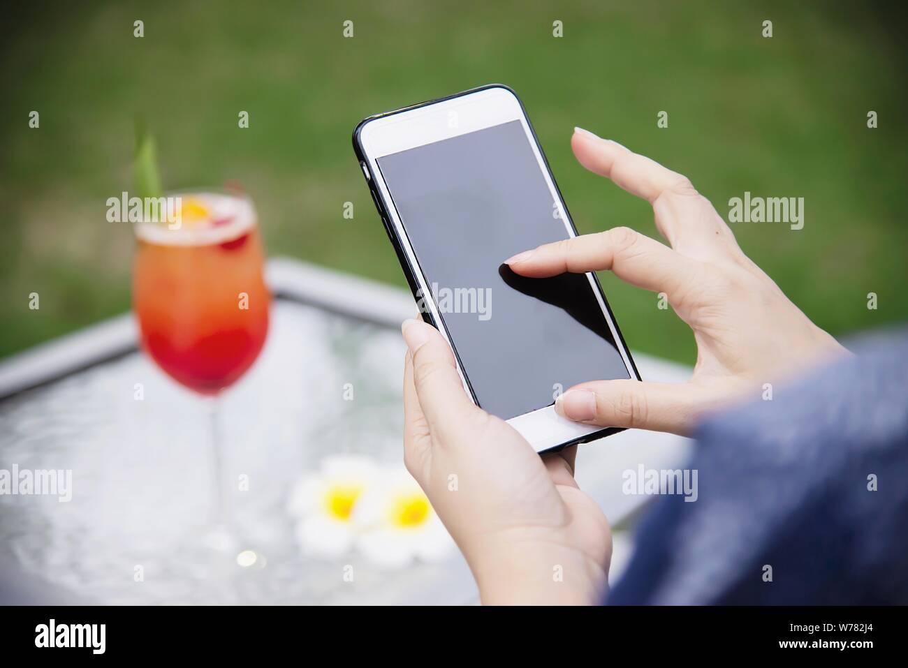 Lady using mobile phone relax in green garden with soft drink ...