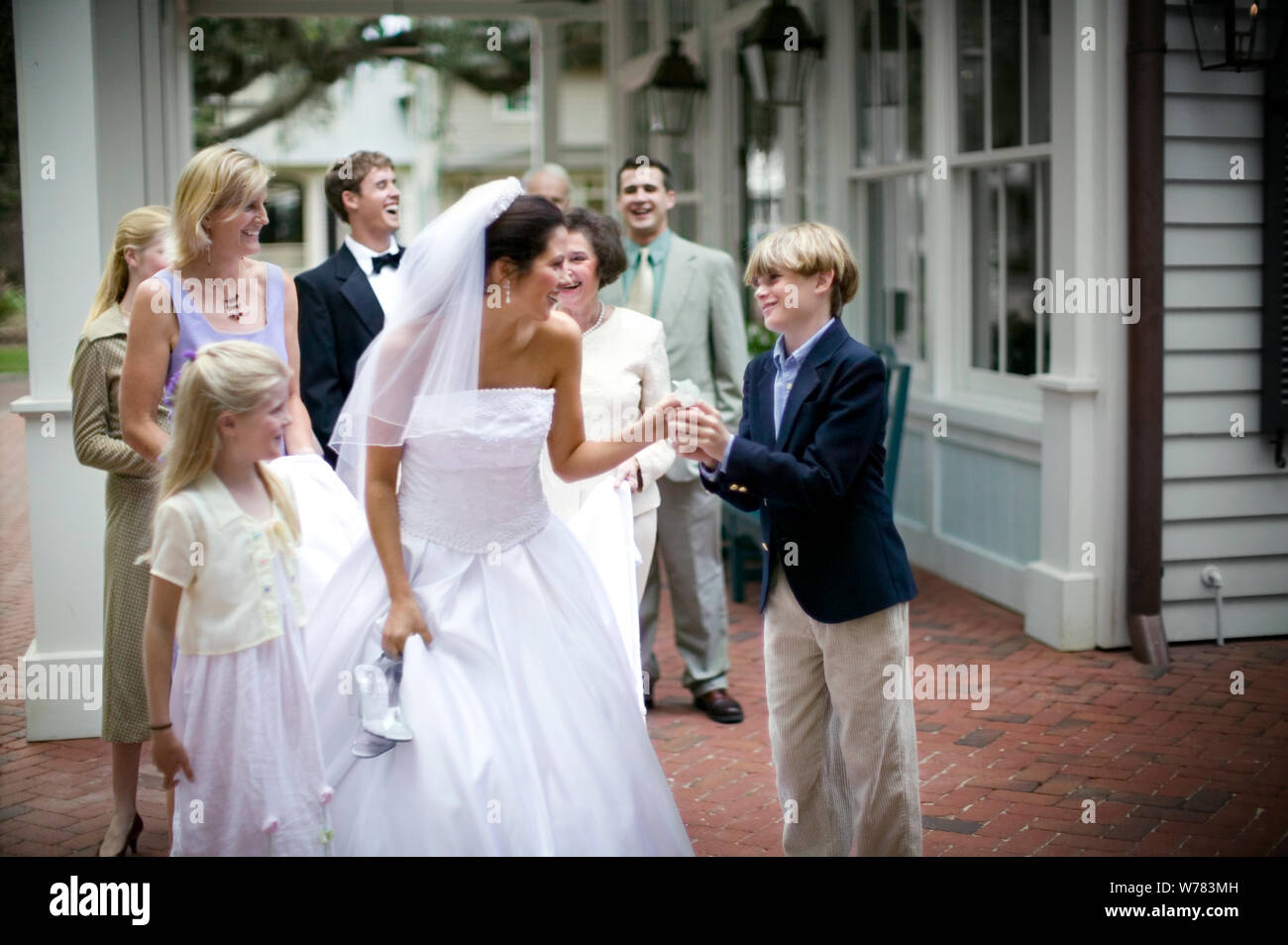 Boy giving a flower to a young adult bride as family look on Stock ...