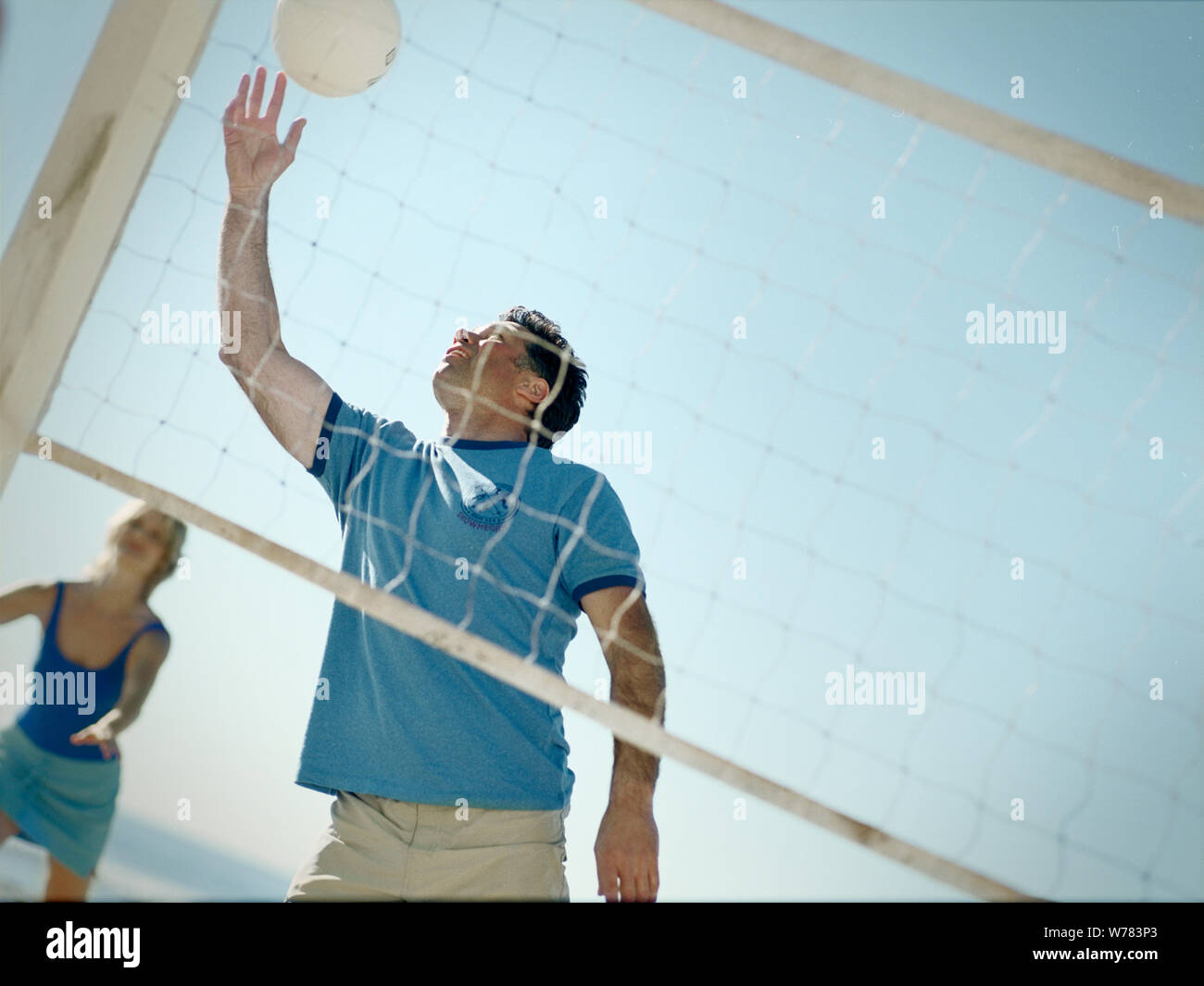 Man reaching up towards a volley ball while standing behind a ...