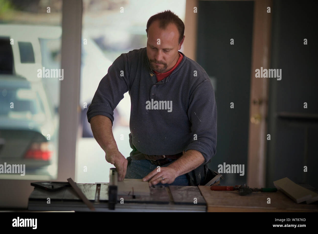 Male builder measuring a piece of wood on a work bench Stock Photo - Alamy