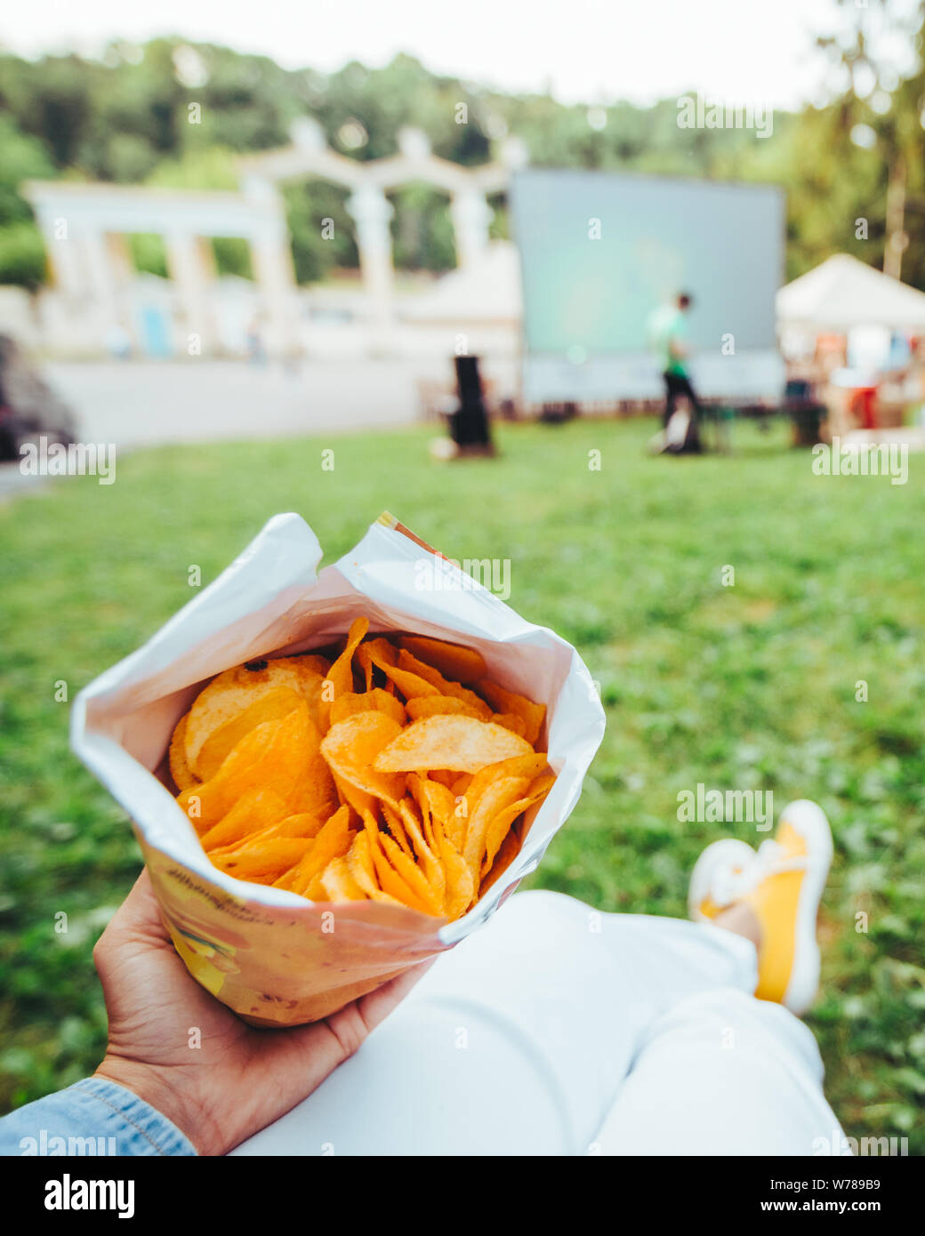 man hands holding chips eating while watching movie in open air cinema ...