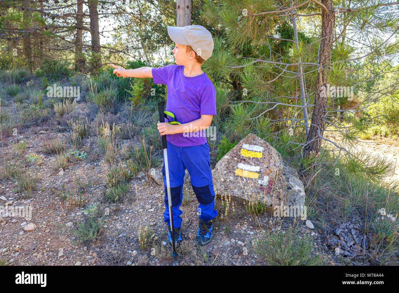Child hiker next to a stone with markings and direction signs of the ...
