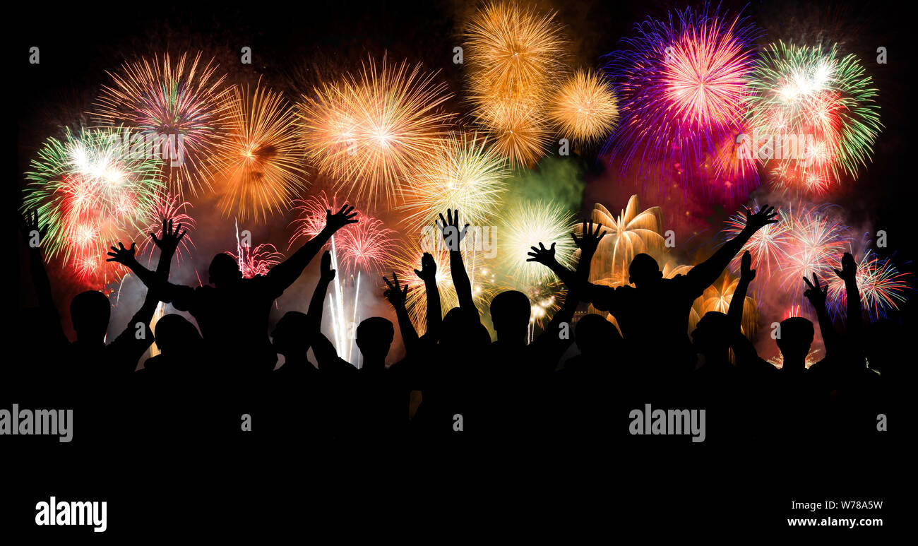 Group of people enjoying spectacular fireworks show in a carnival or ...