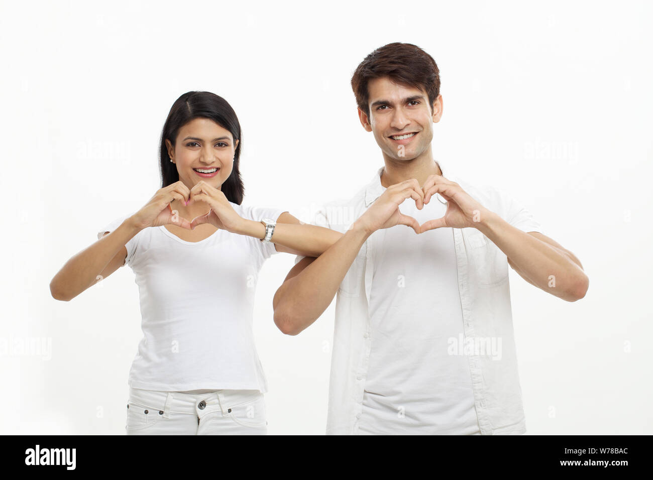 Young couple making heart shape with hands and smiling Stock Photo - Alamy