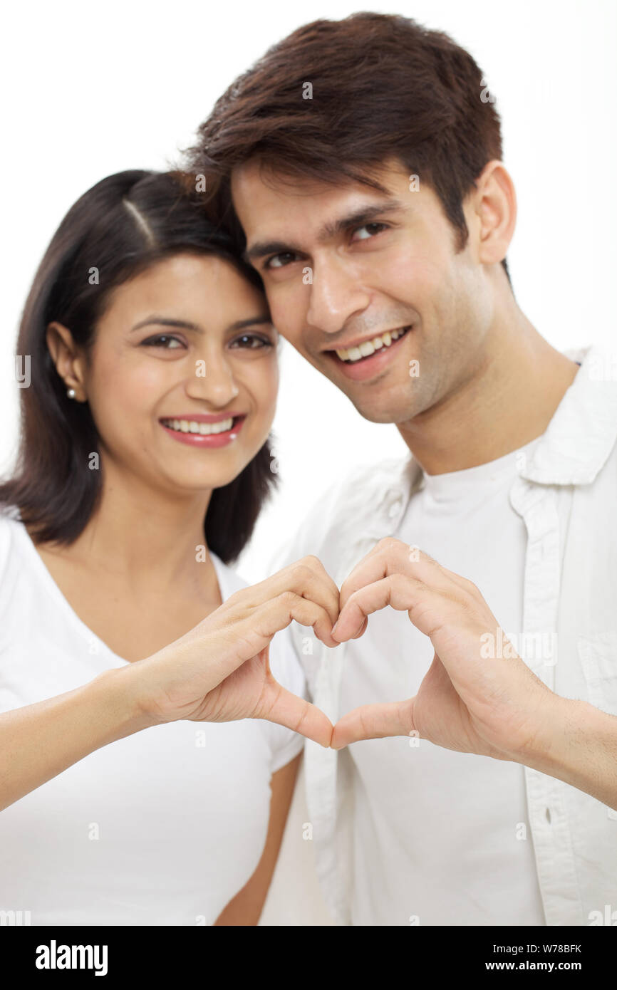 Young couple making heart shape with hand and smiling Stock Photo - Alamy