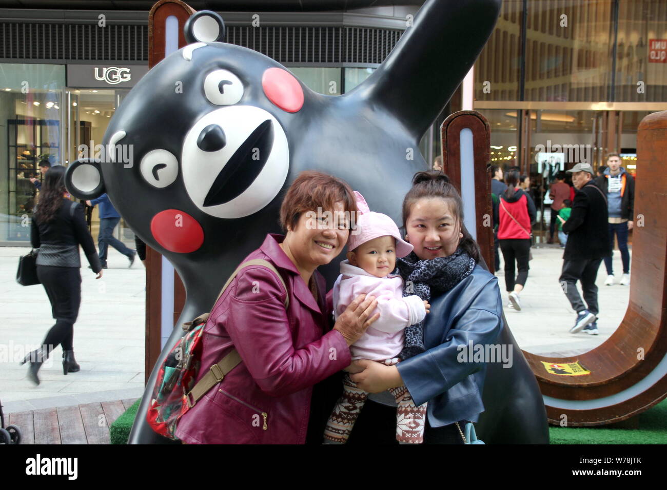 Chinese visitors pose with a Kumamon sculpture for photos at the ...