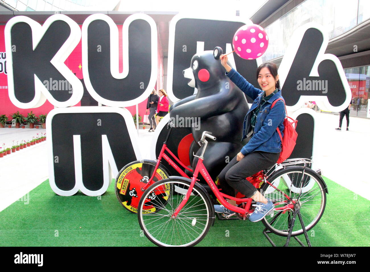 A visitor poses with a Kumamon sculpture for photos at the exhibition ...