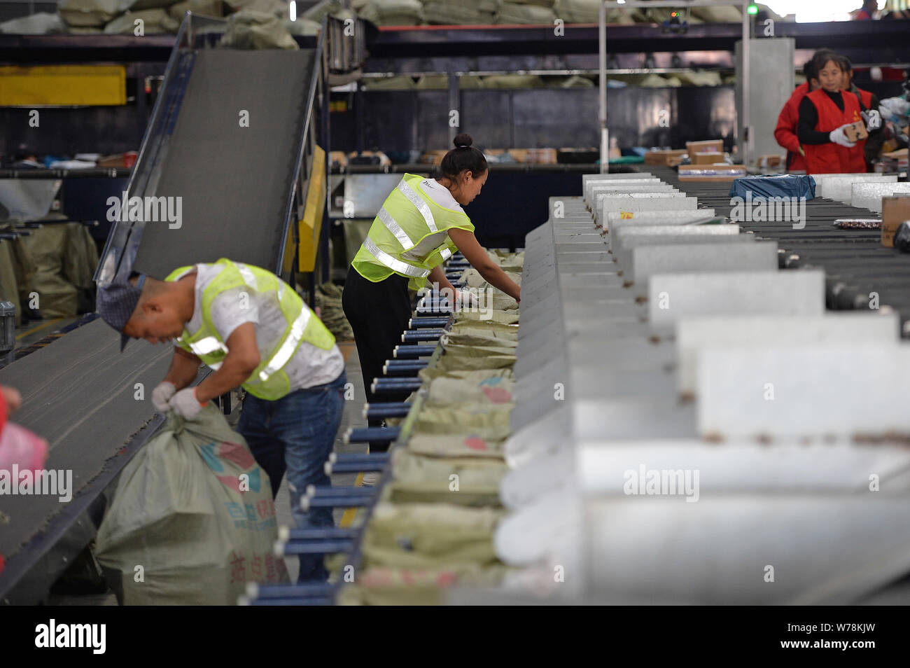 Chinese workers sort out piles of parcels, most of which are from ...
