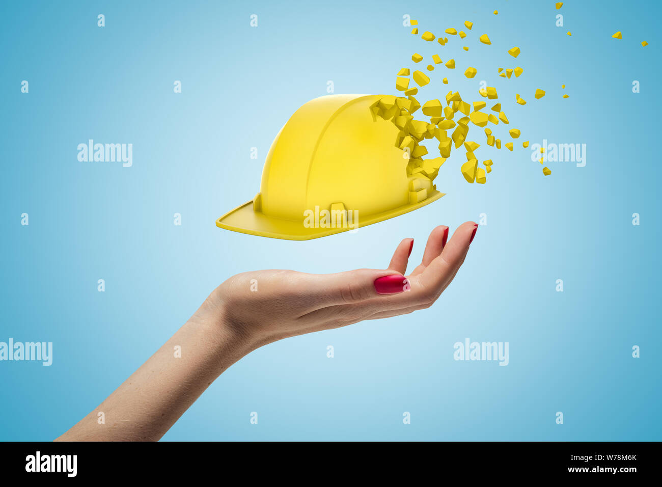 Female hand with yellow construction hard hat shattering into pieces on ...