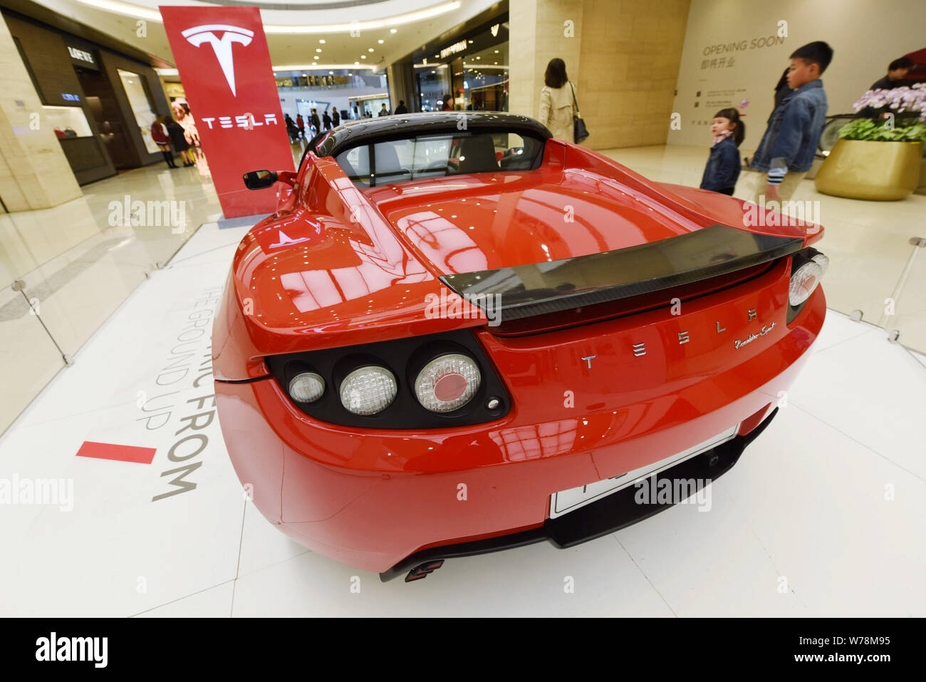 Customers look at a Tesla Roadster, a battery electric vehicle (BEV ...