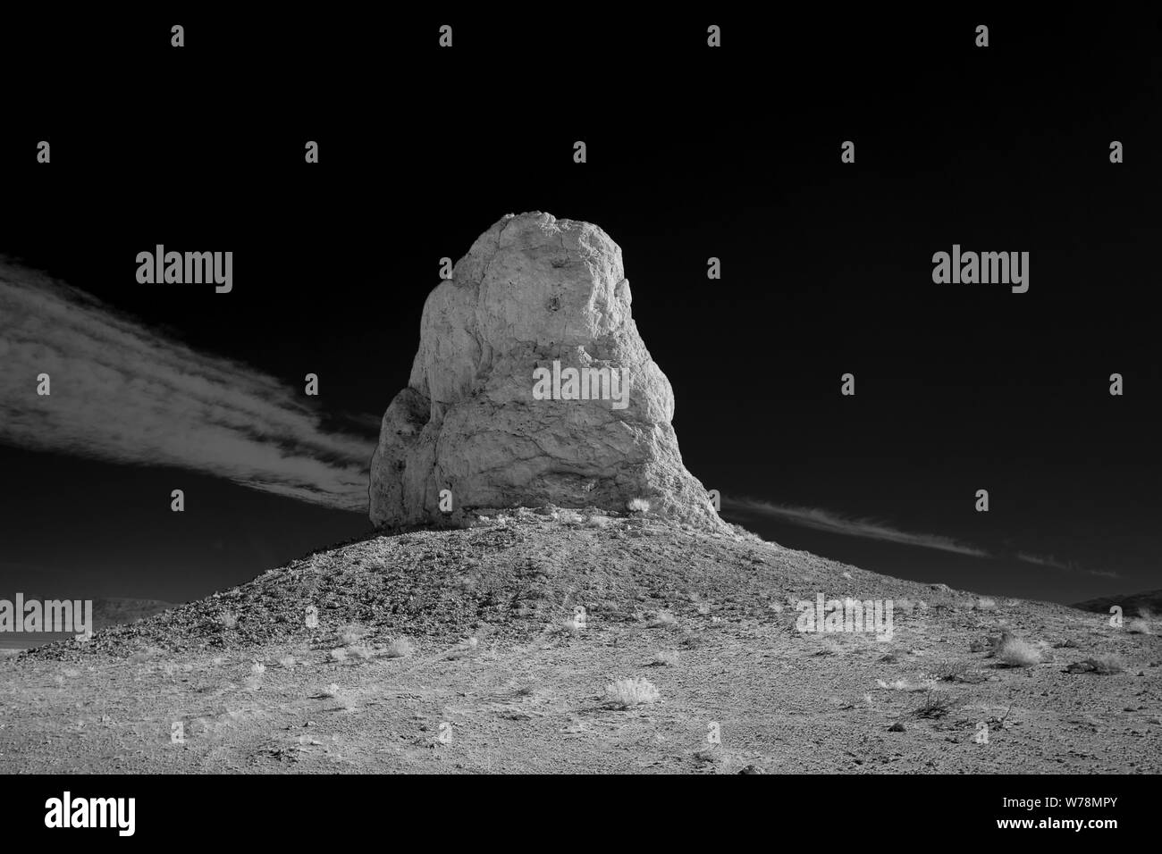 Stone pinnacle on top of hill under black skies with white clouds Stock ...