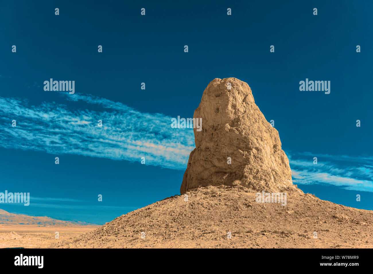 Single large rock formation on top of barren brown desert hill top ...