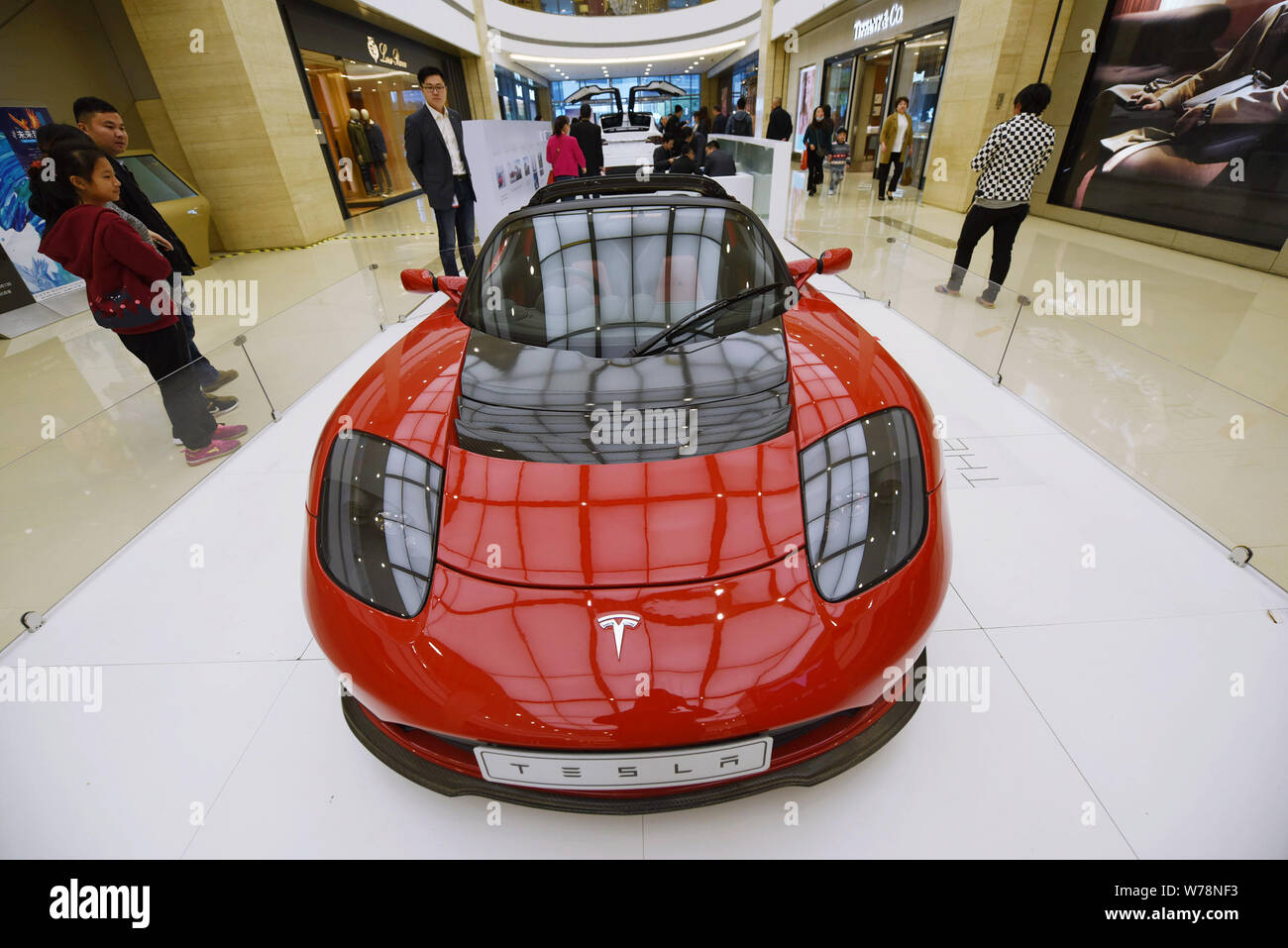 Customers look at a Tesla Roadster, a battery electric vehicle (BEV ...