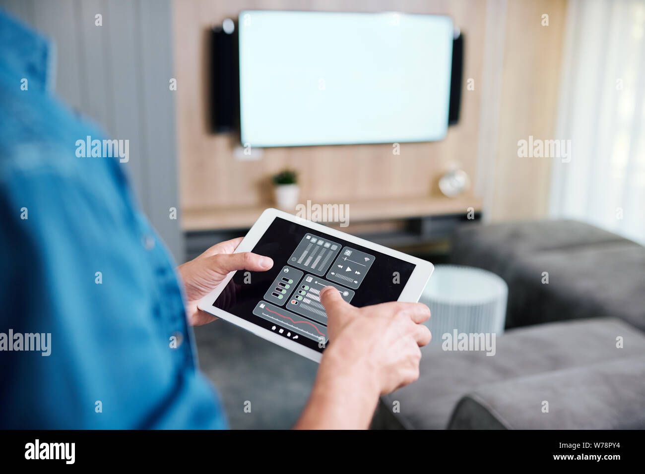Hands of young man holding tablet with smart remote control system ...
