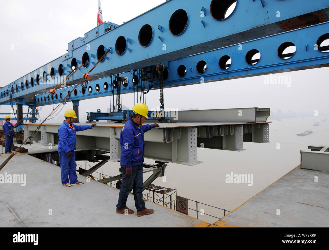 Chinese workers install the last steel bridge deck at the site of a ...
