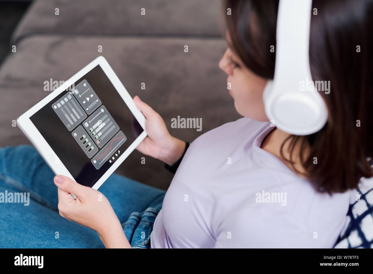 Contemporary young woman using smart remote control application Stock ...