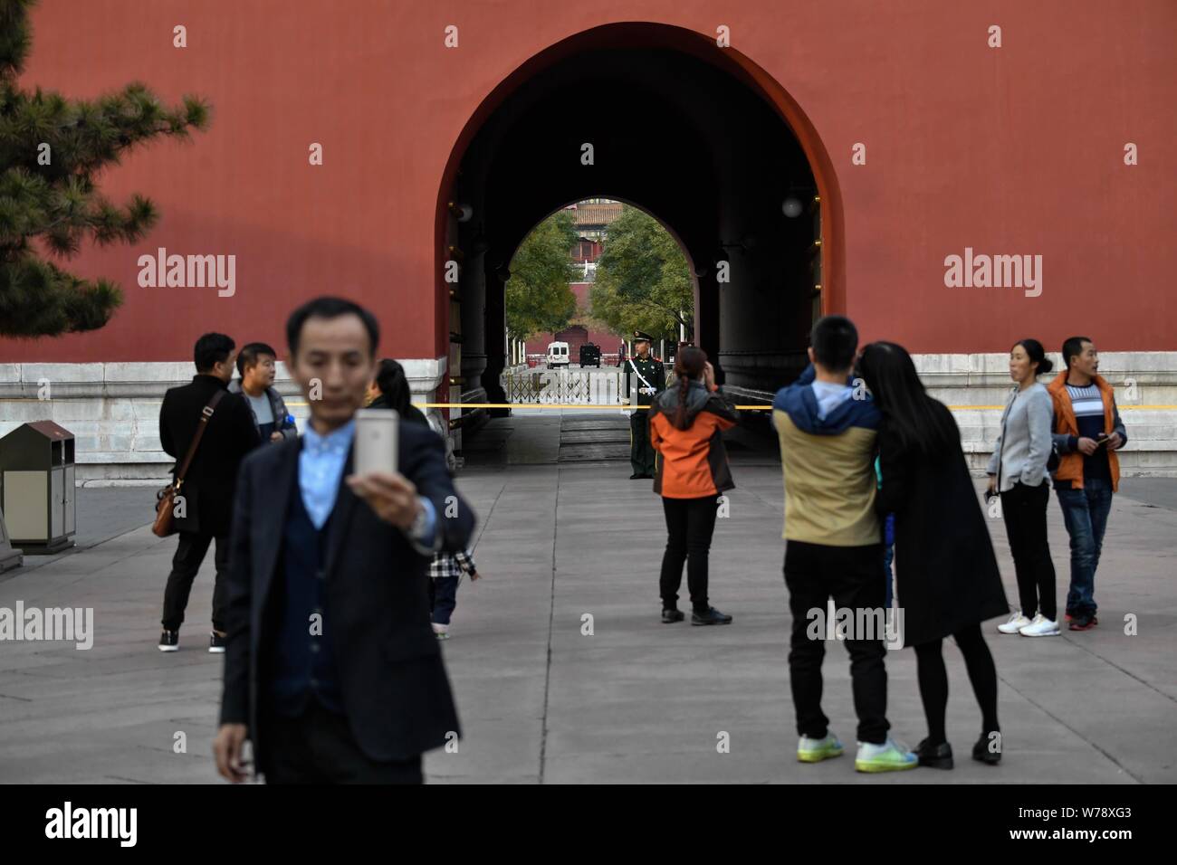 Tourists pose for photos in front of a gate of the Palace Museum, also ...