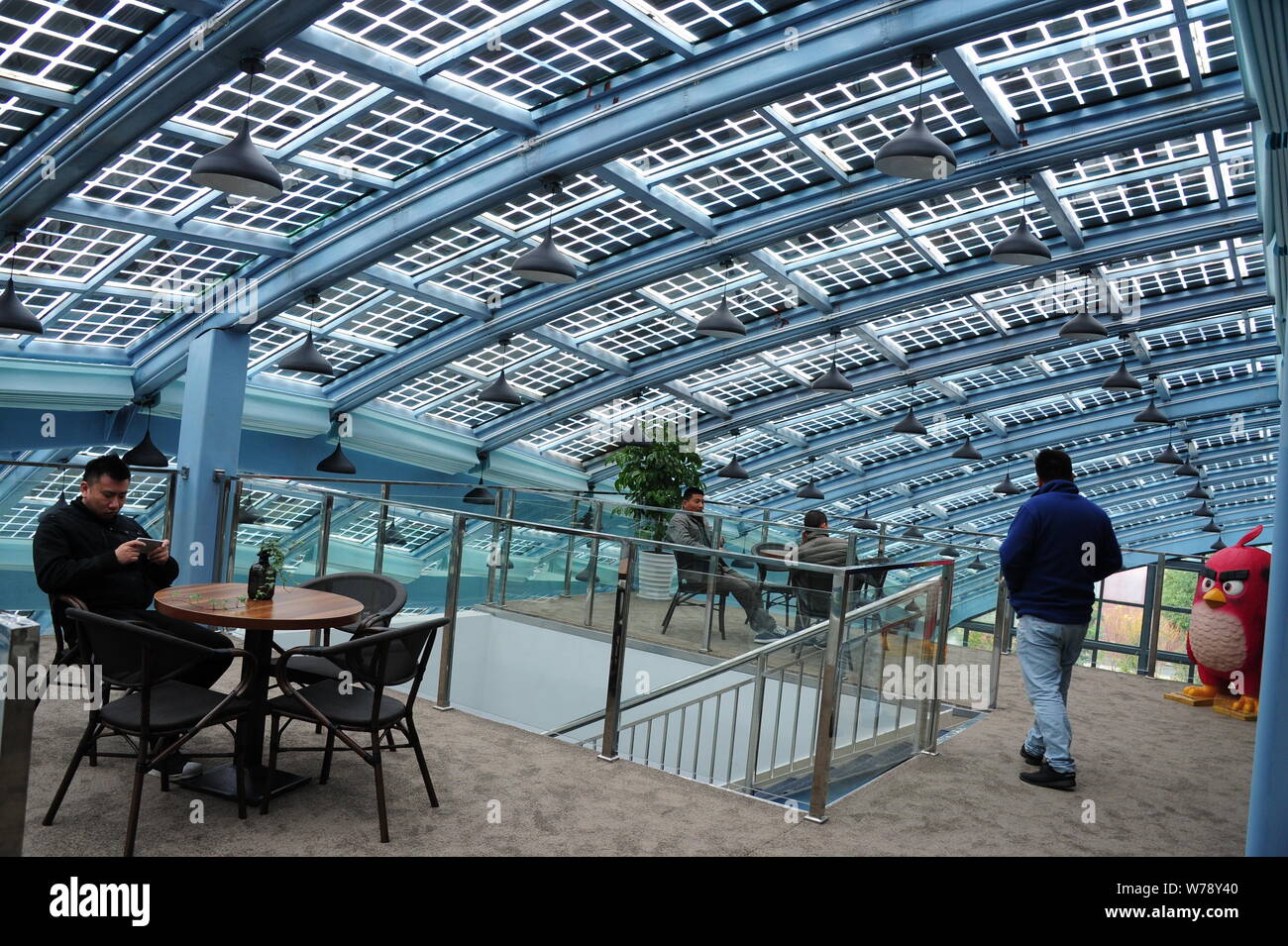 Local residents wait in the China's largest solar photovoltaic super charging station of Tellus ...