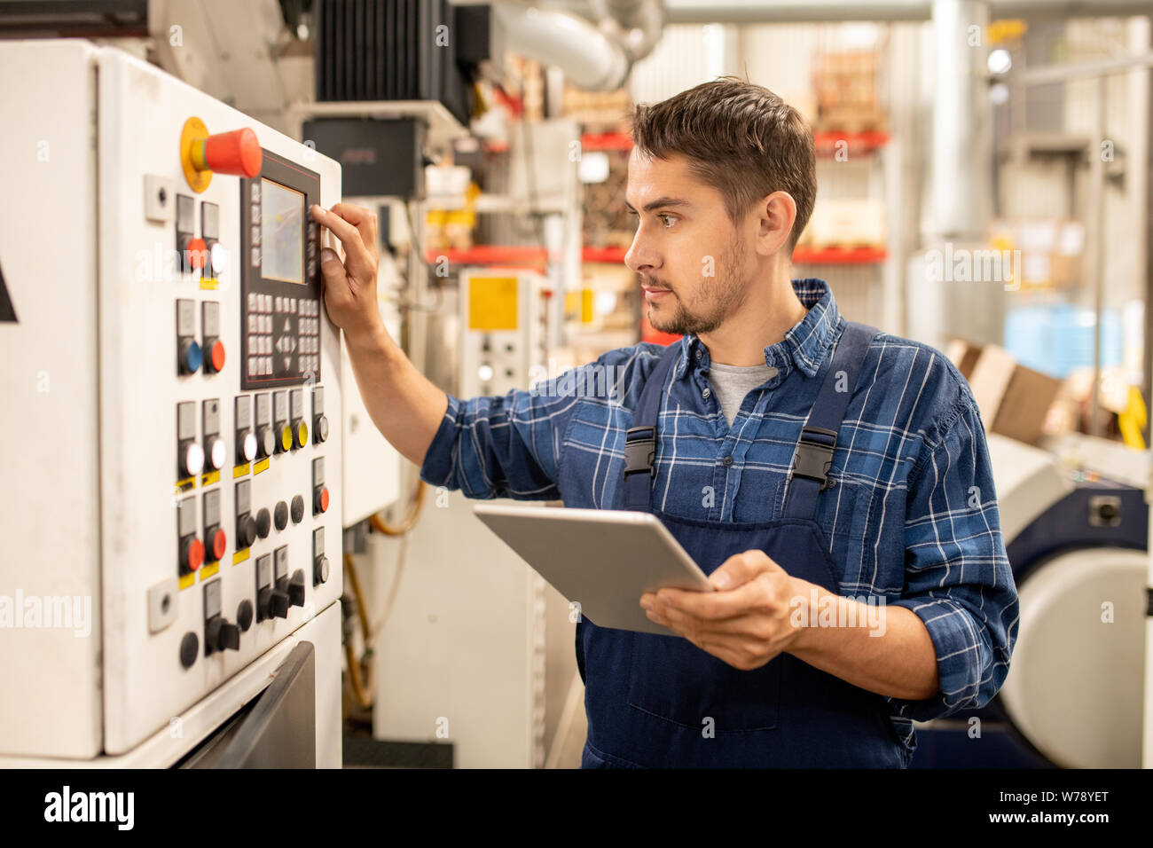 Young engineer checking data on control panel while setting working ...