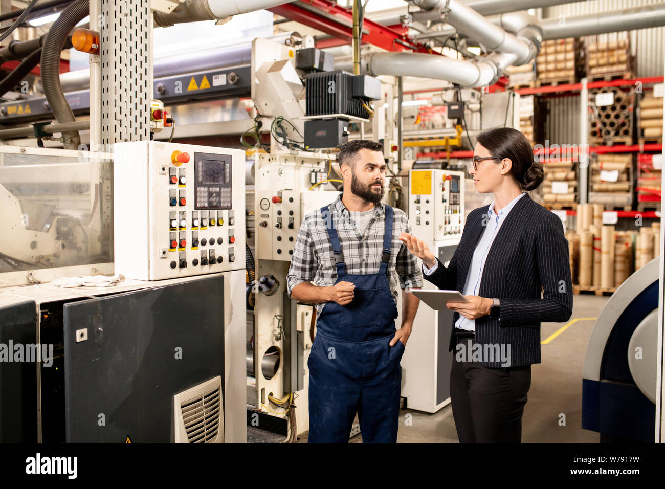 Two young business partners discussing working methods of industrial ...