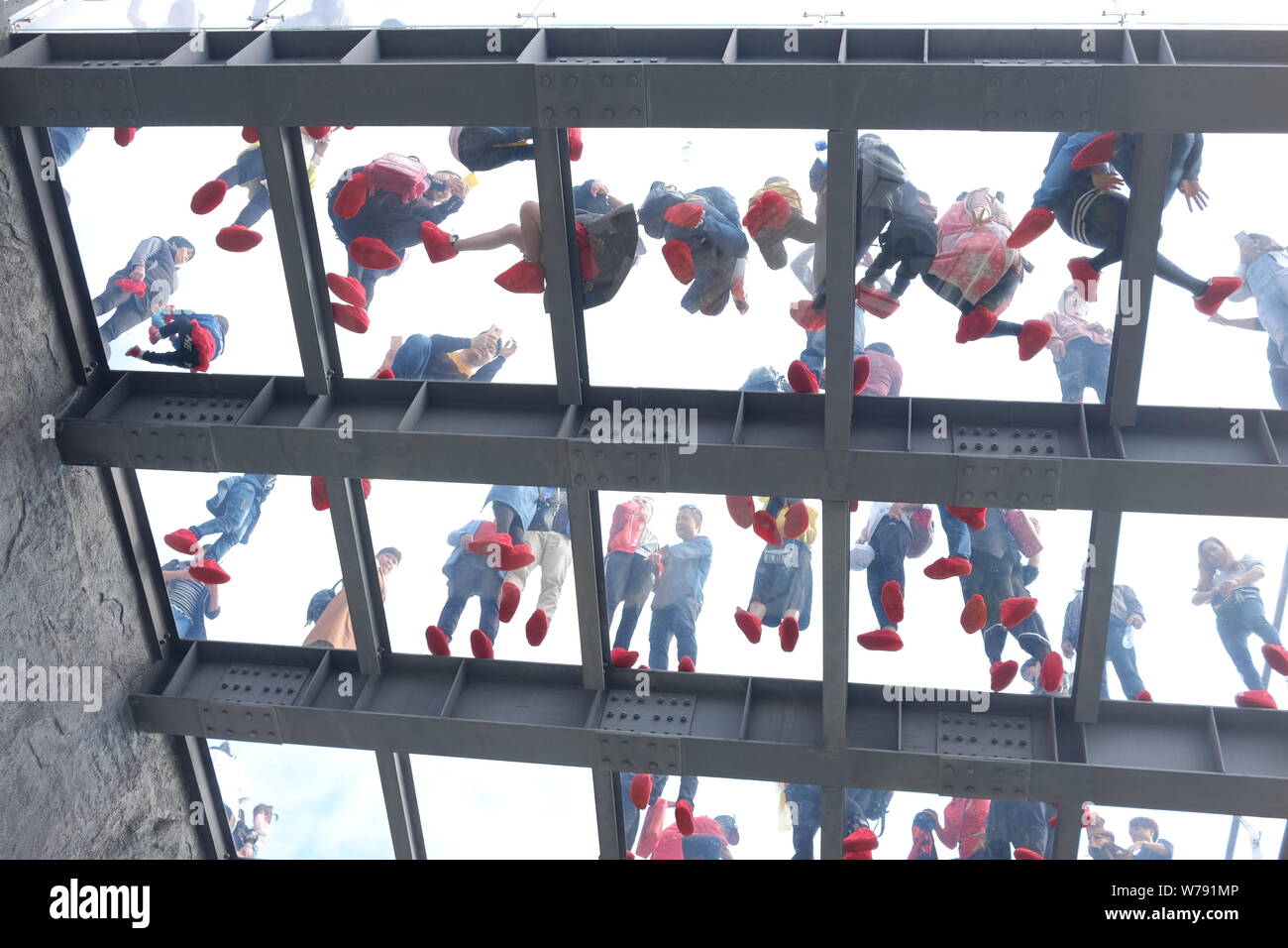 Visitors walk on a glass walkway along the edge of a cliff at the ...