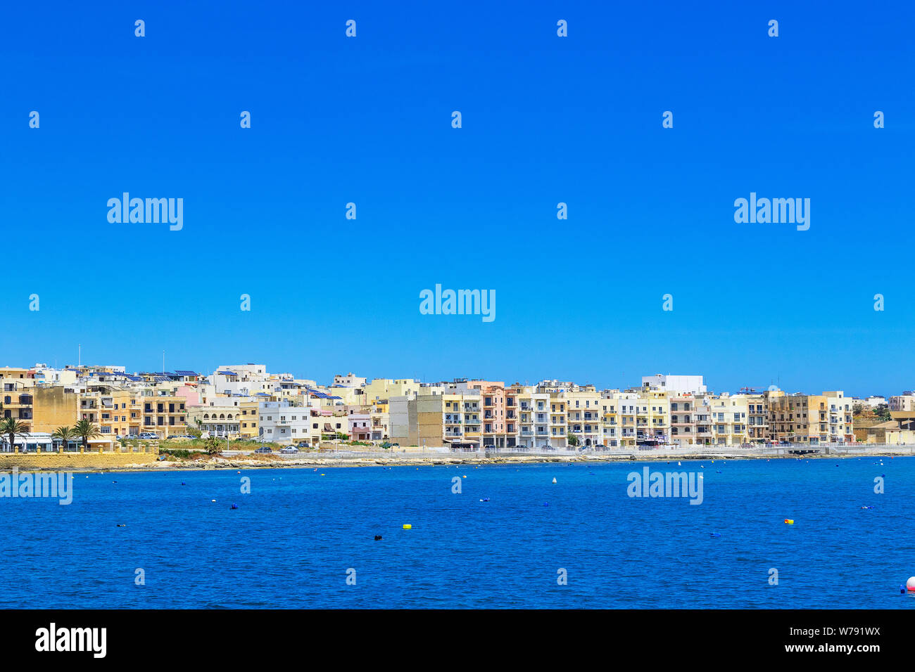 Pretty Bay beach in Birzebbuga with colorful houses on coastline, sandy ...