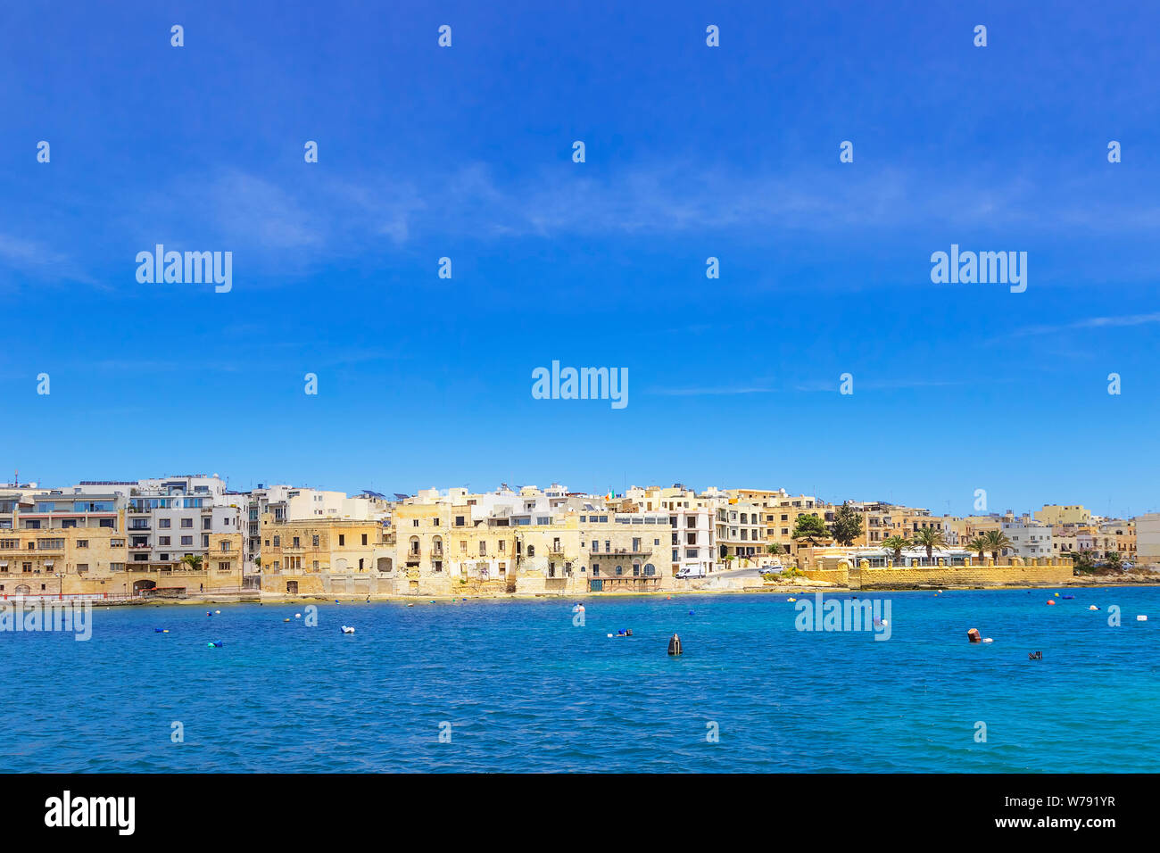 Pretty Bay beach in Birzebbuga with colorful houses on coastline, sandy ...