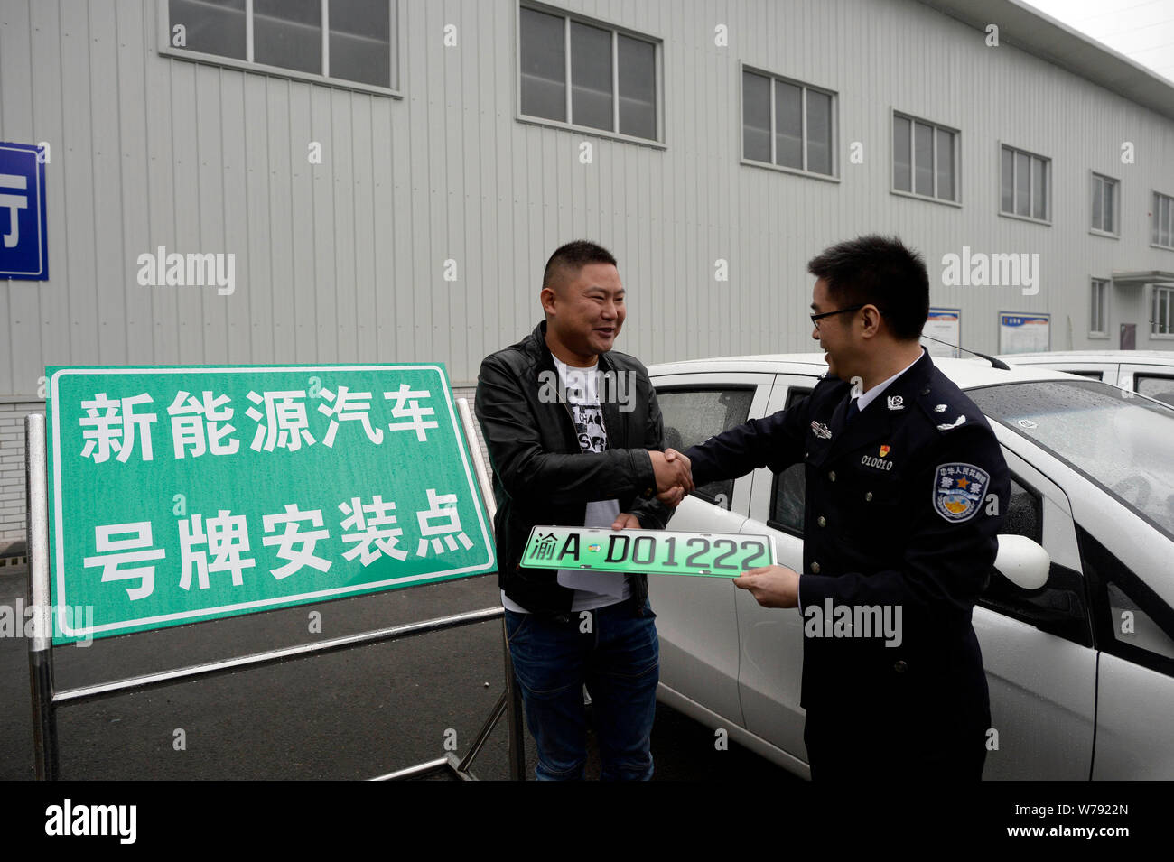 A policeman gives the first green license plate for new energy vehicles ...