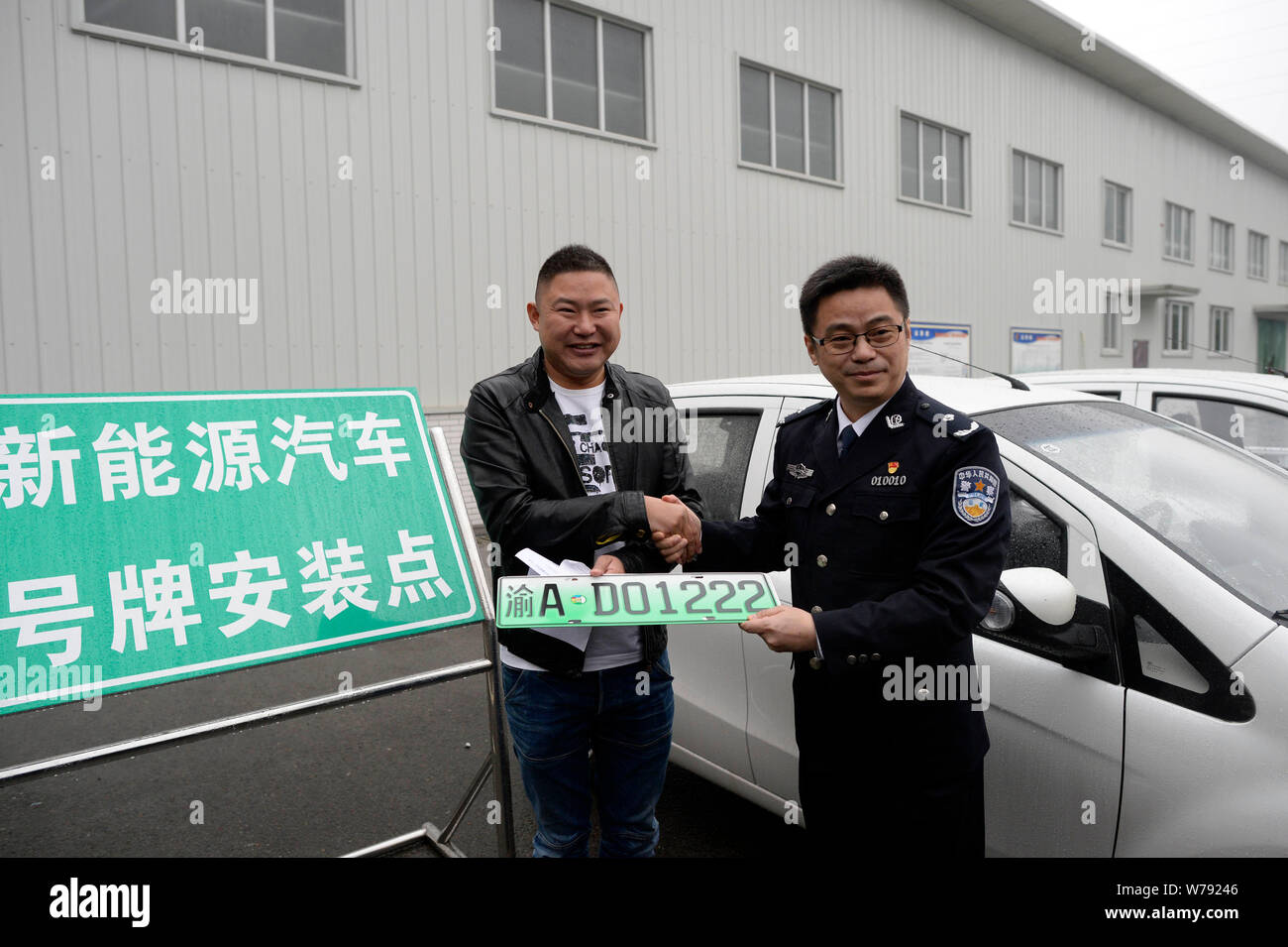 A policeman gives the first green license plate for new energy vehicles ...