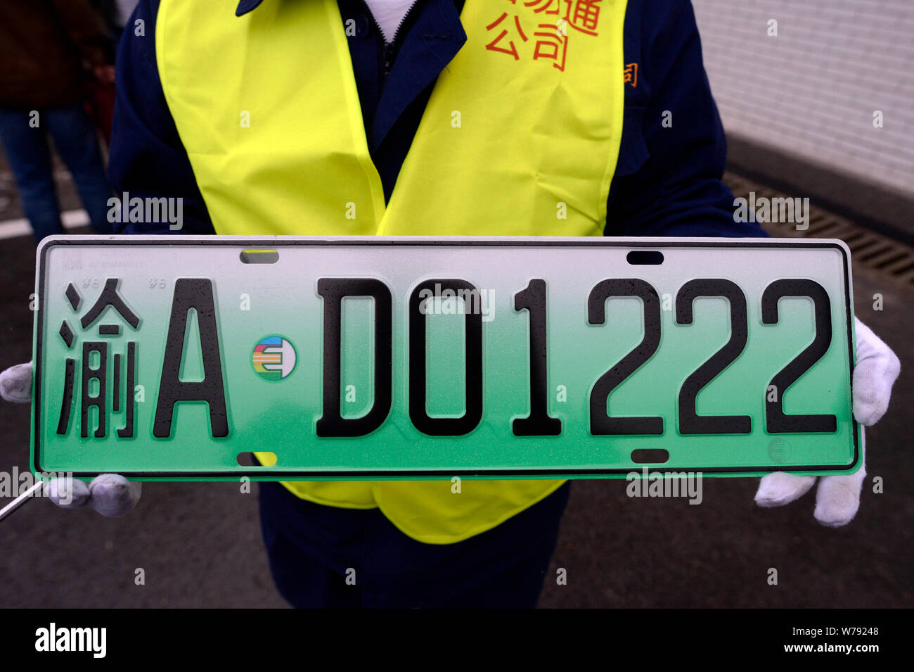 A staff displays the first green license plate for new energy vehicles ...