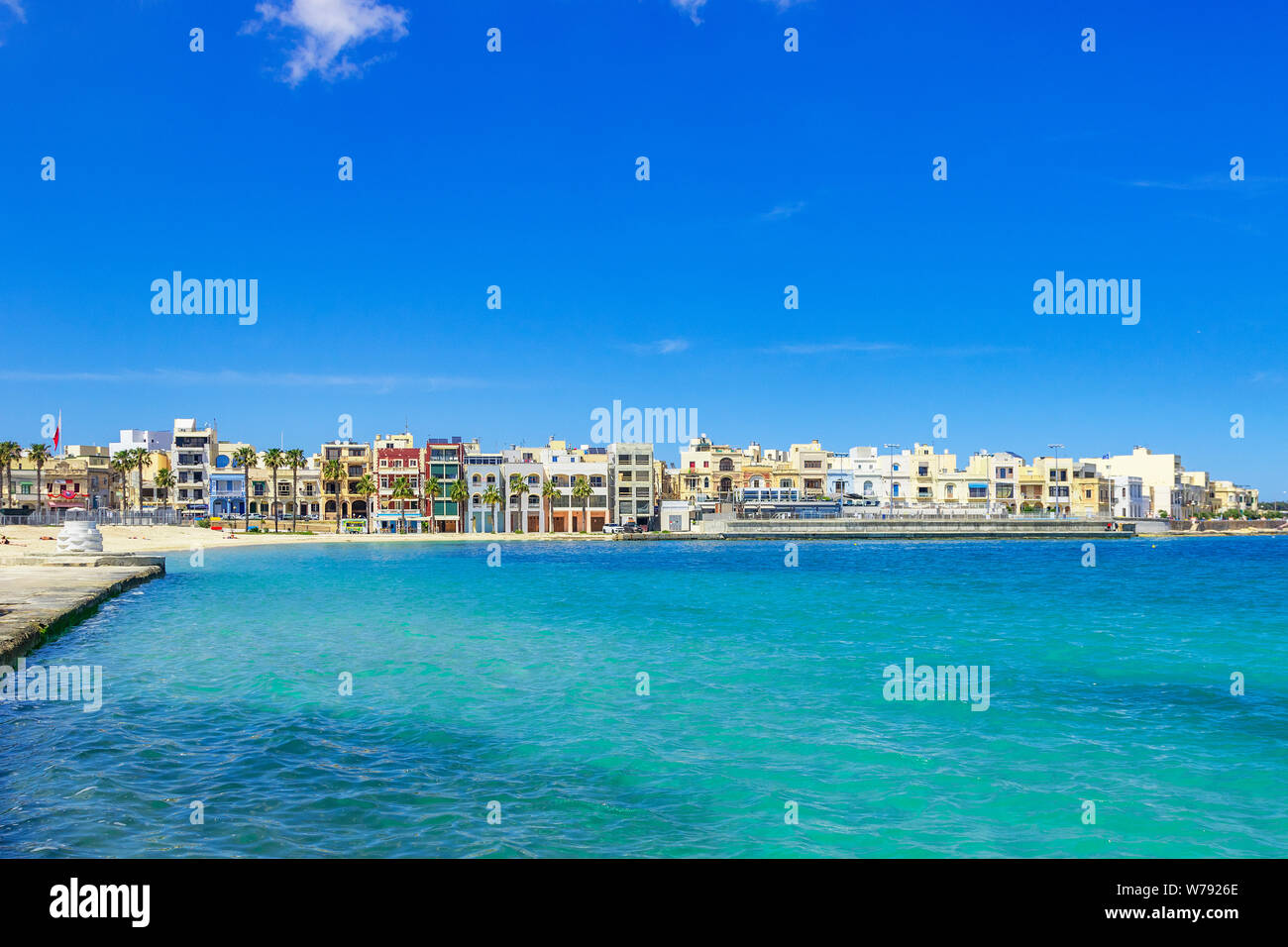 Pretty Bay beach in Birzebbuga with colorful houses on coastline, sandy ...