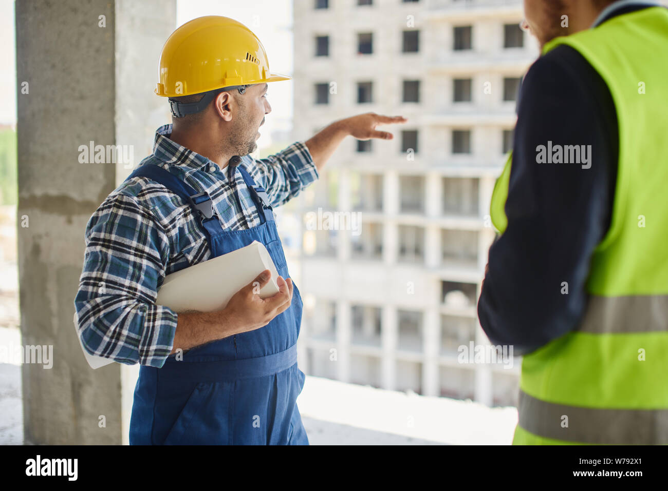 Two engineers discuss work related questions together holding folded ...