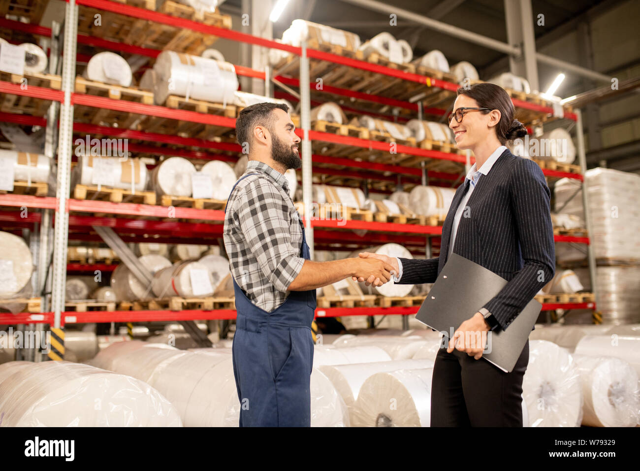 Successful partners handshaking in warehouse of large factory after ...