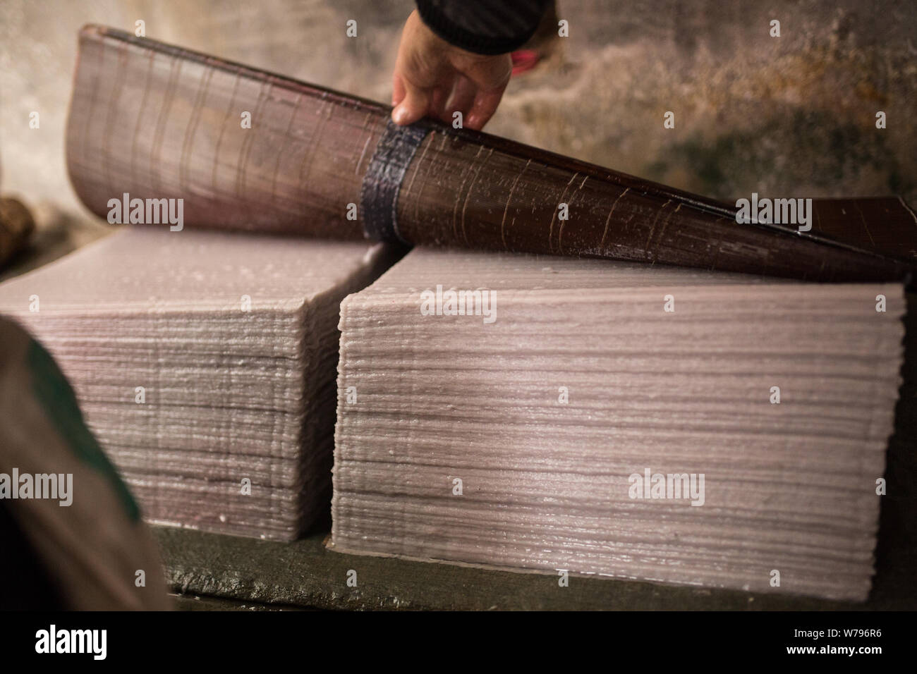 A Chinese worker shows stacks of wet paper made with traditional crafts ...