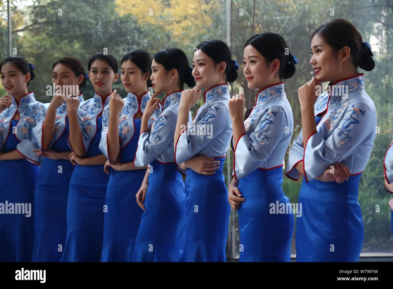 Chinese volunteers wearing cheongsam (qipao) pose during a ceremony for ...