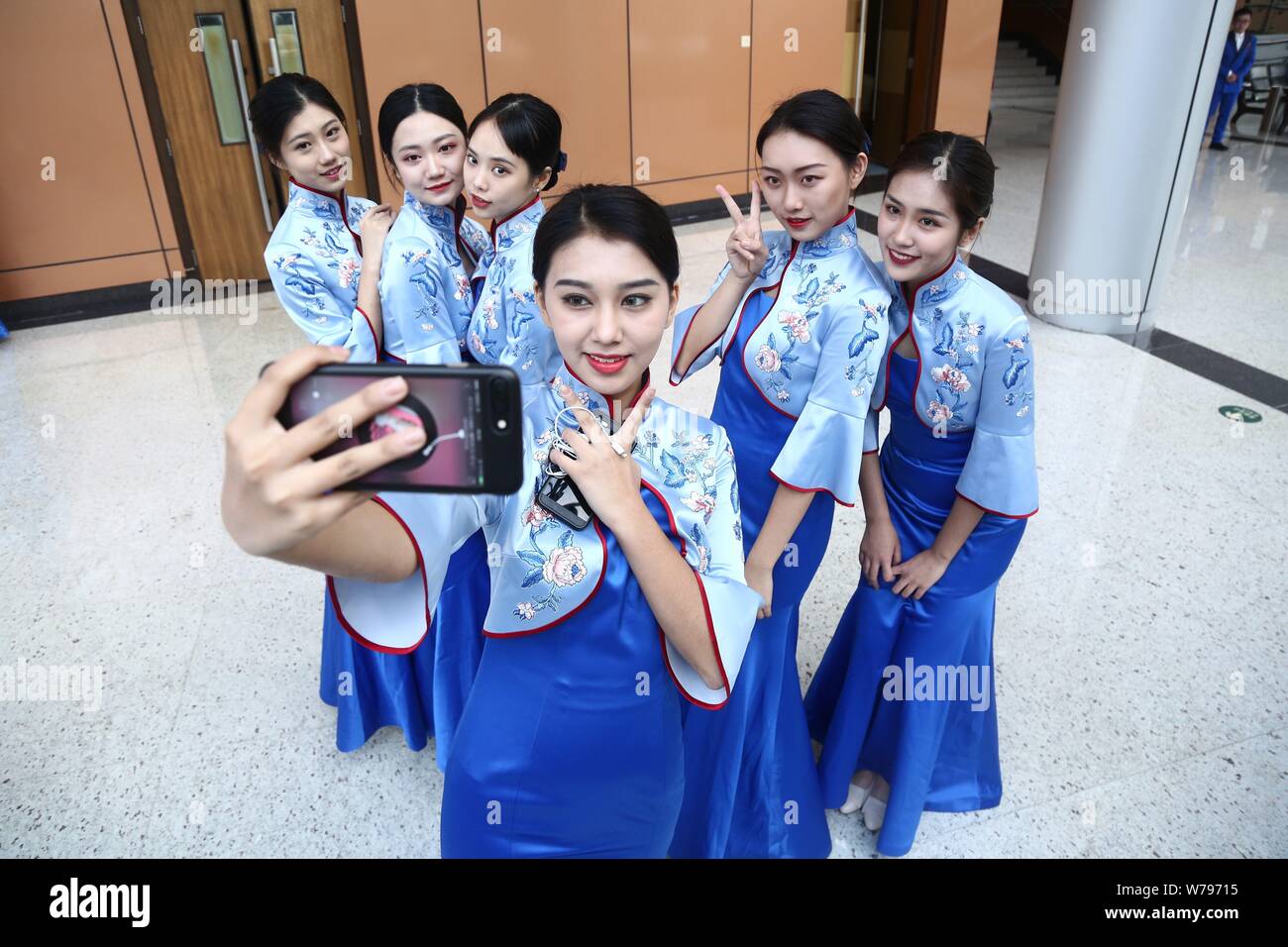 Chinese volunteers wearing cheongsam (qipao) pose during a ceremony for ...