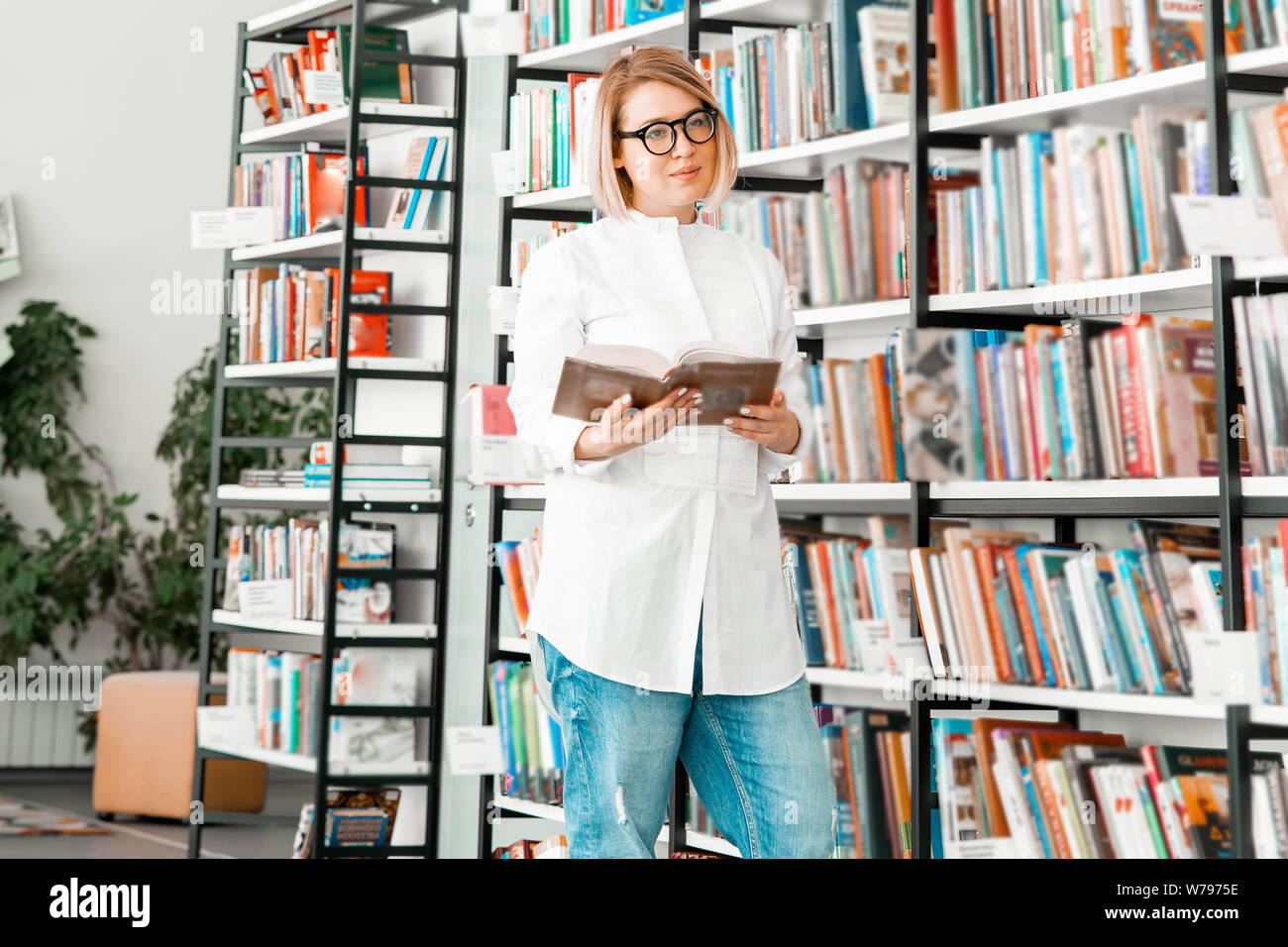 Young pensive attractive woman with glasses in formal clothes reading a ...