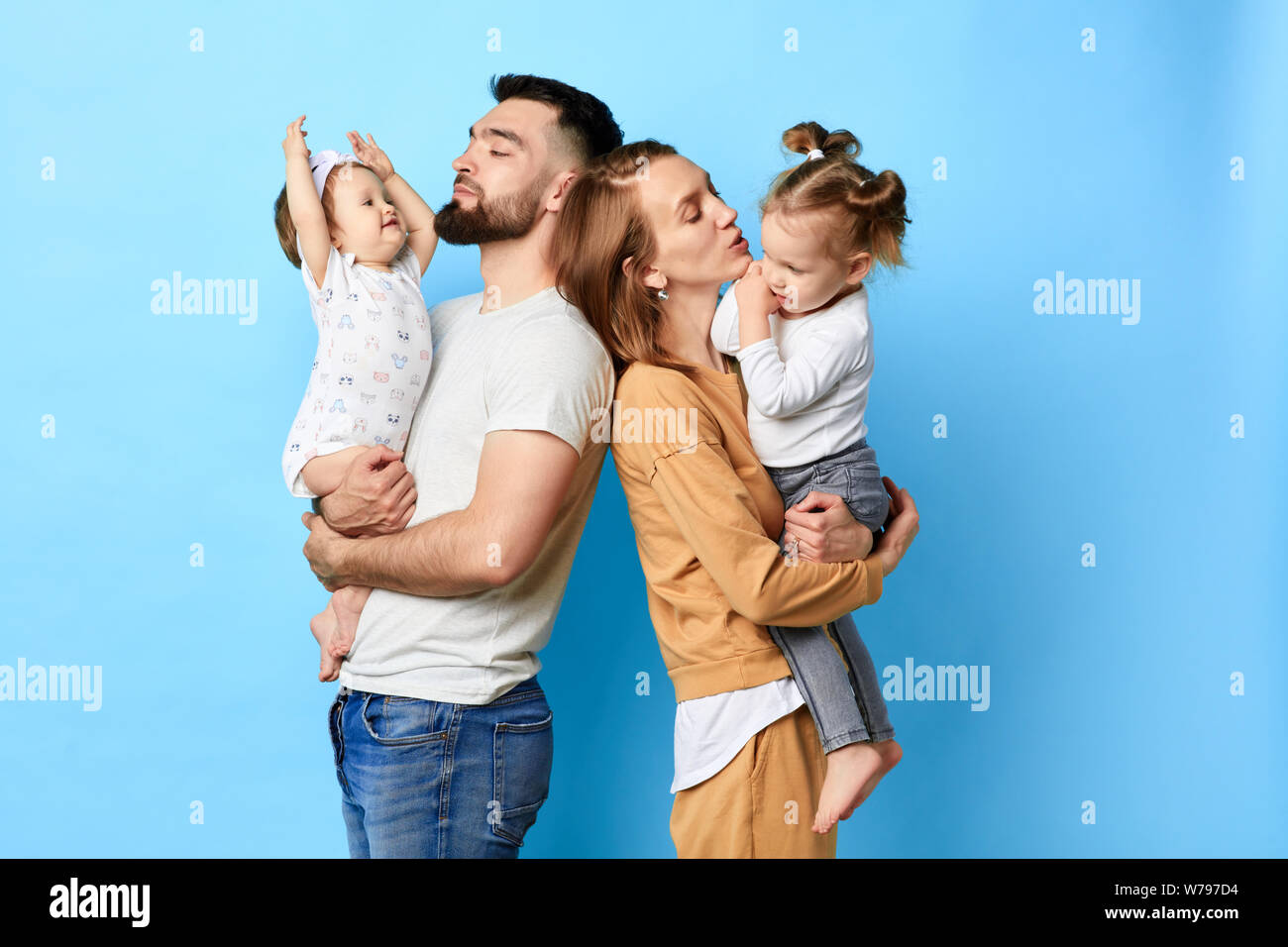 two caring parents standing back to back and holding their children in ...