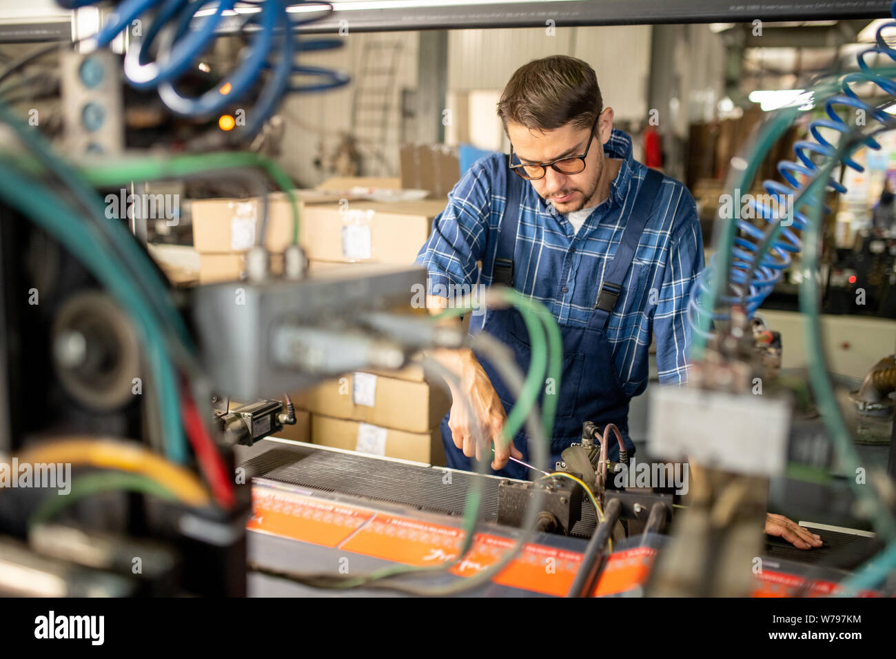 Young repairman or technician serving broken industrial machine Stock ...