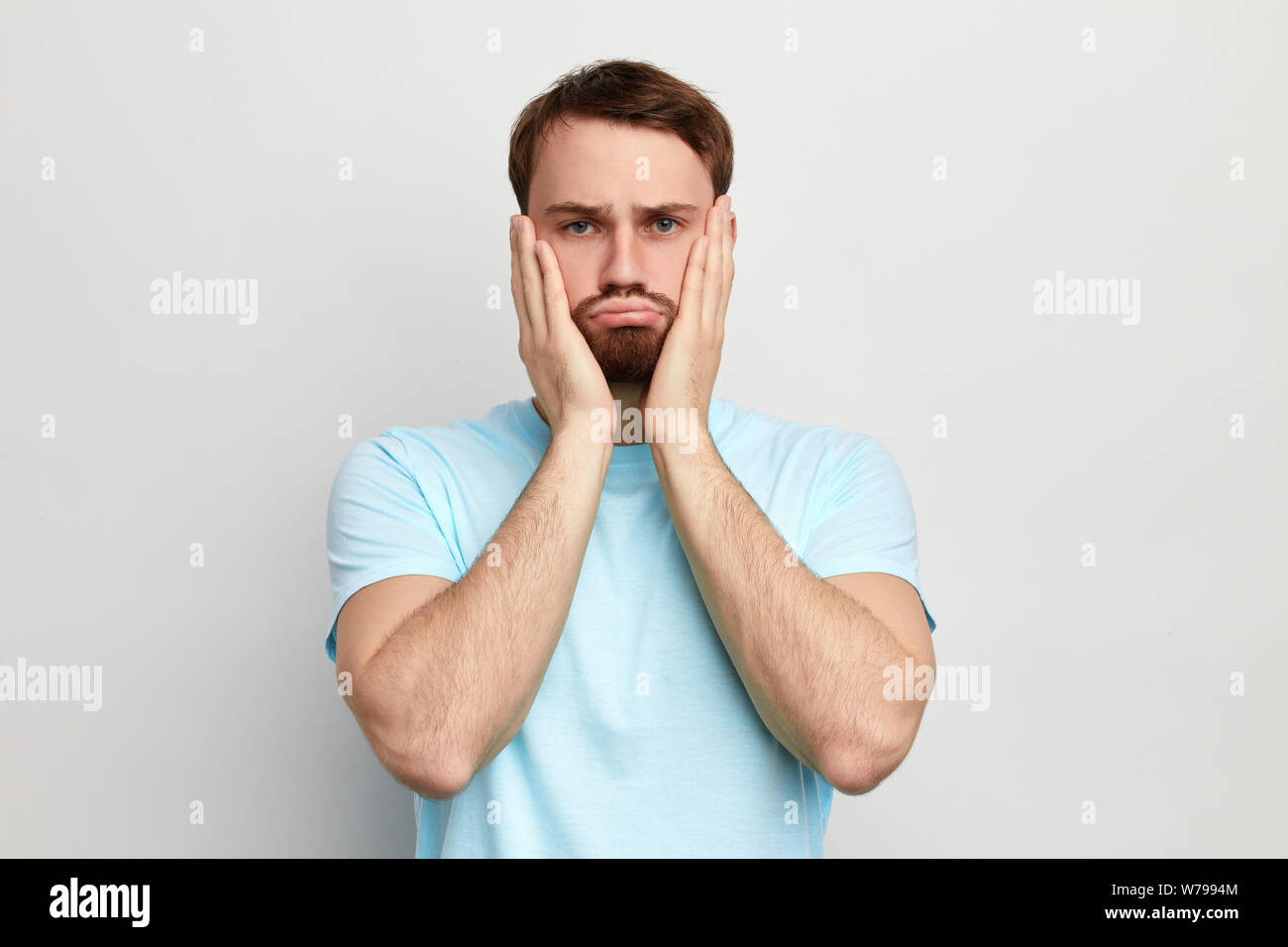 depressed young man with blue eyed male keeping palms on cheek ...