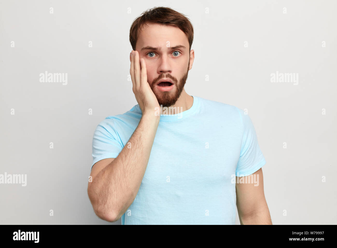 Shocked excited impressed man with a palm on his cheek, opened mouth in ...