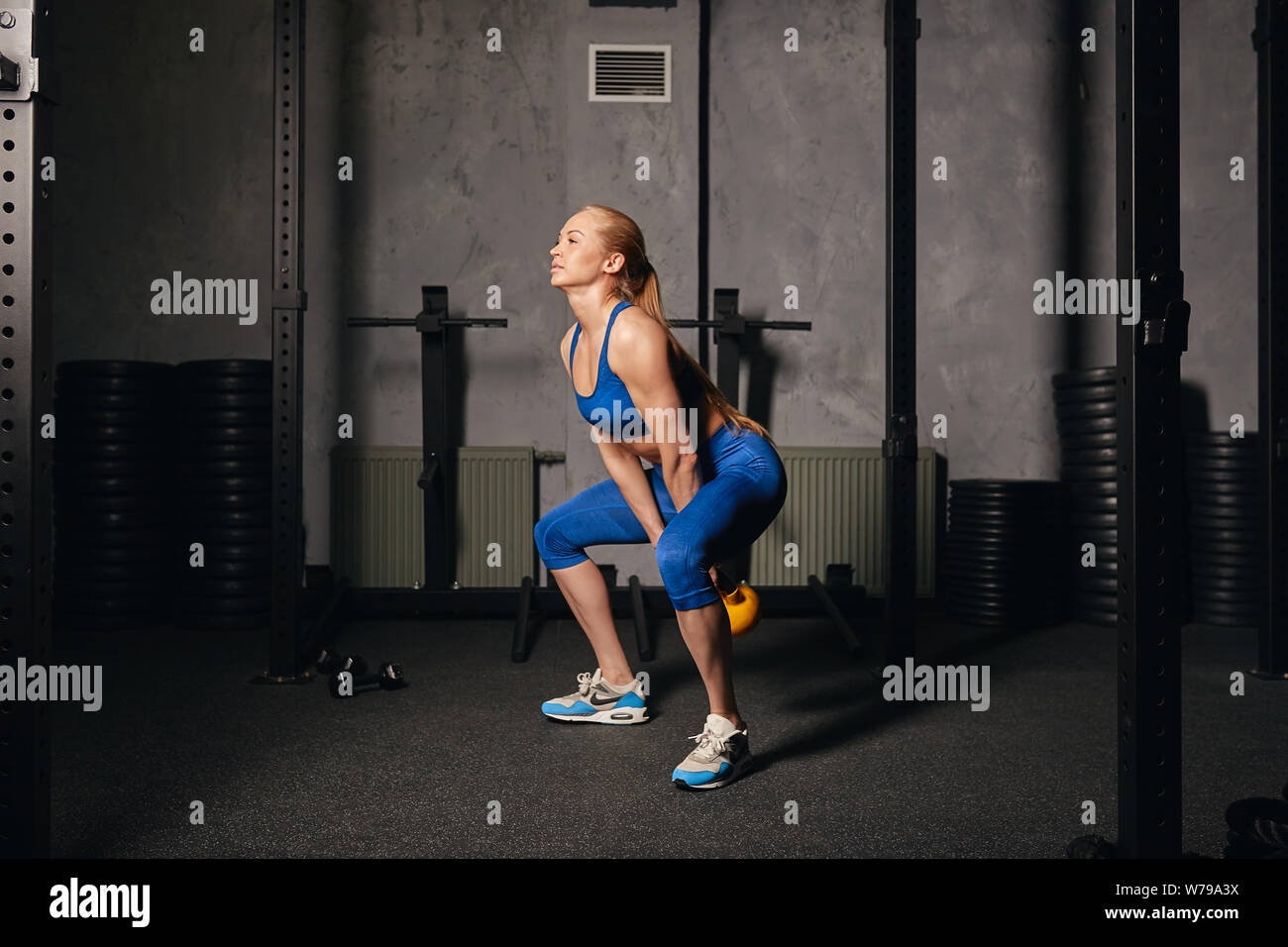 Athletic motivated strong woman exercising with kettle bell while being ...
