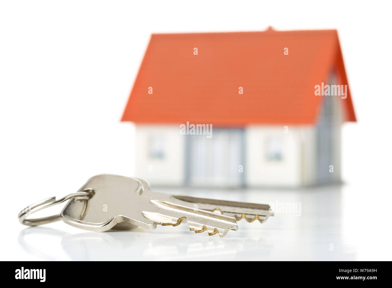 House keys in front of model house over white background with selective ...
