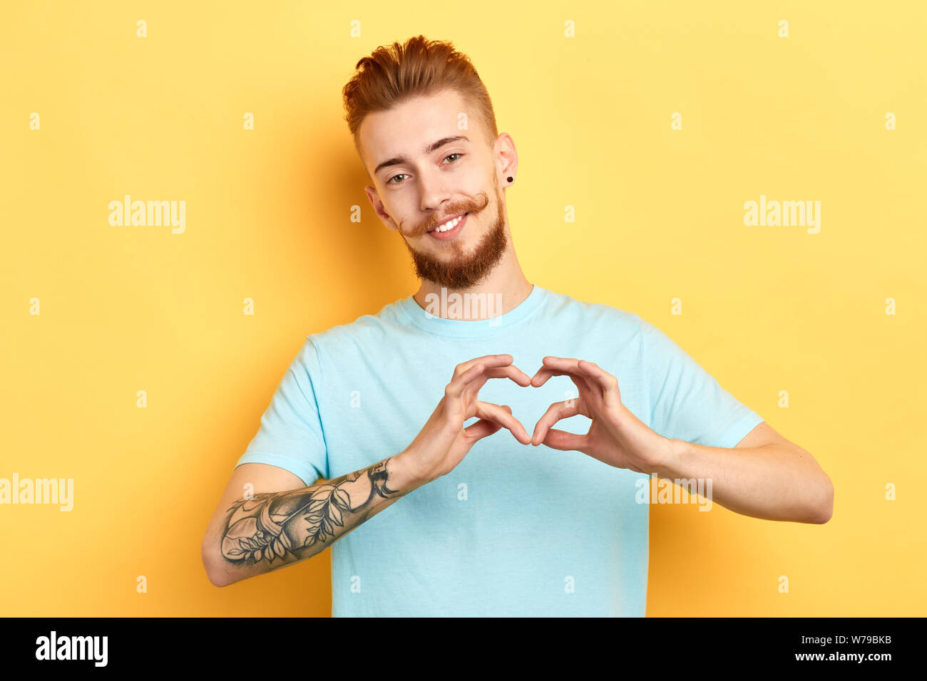 stylish funny man with creative moustache showing a sign of a heart ...