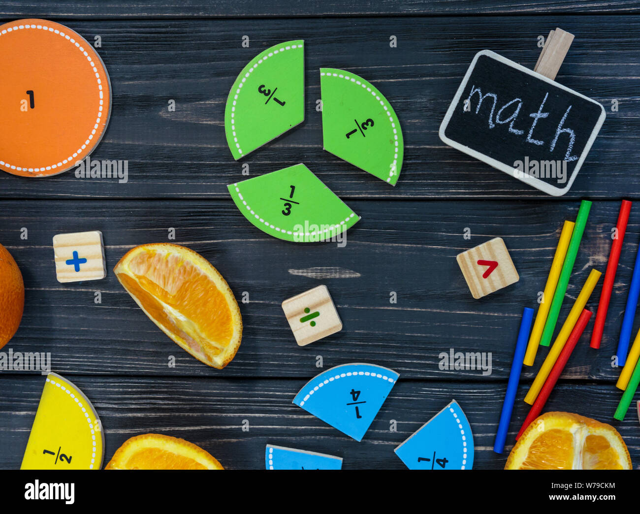 Сolorful math fractions and oranges as a sample on dark wooden ...