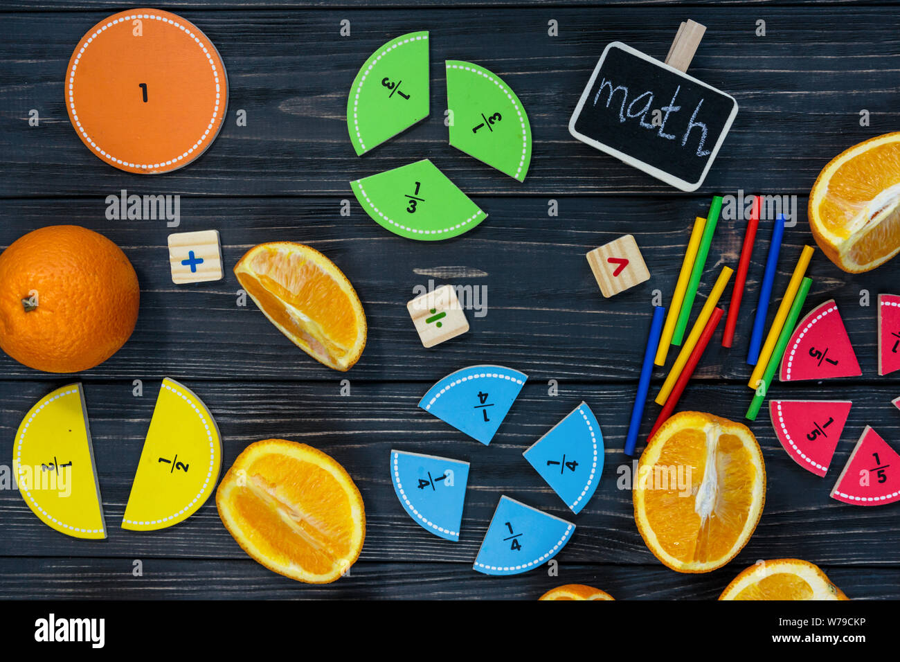 Сolorful math fractions and oranges as a sample on dark wooden ...